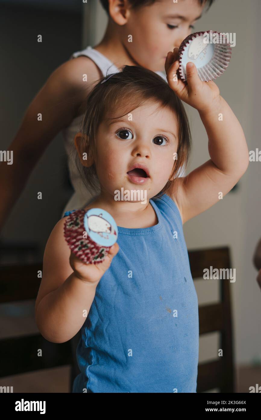 Little adorable baby girl sitting in the kitchen holding silicone ...