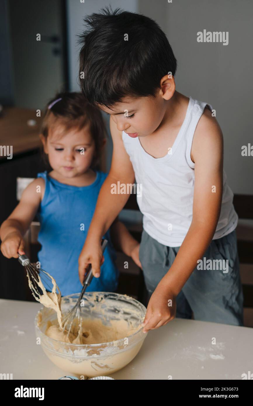Adorable kids having fun together preparing dough for biscuit in the ...