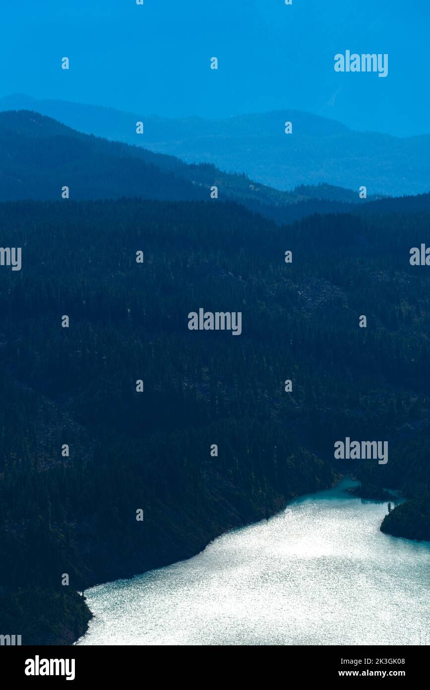Rolling tree covered hills with an alpine lake Stock Photo - Alamy