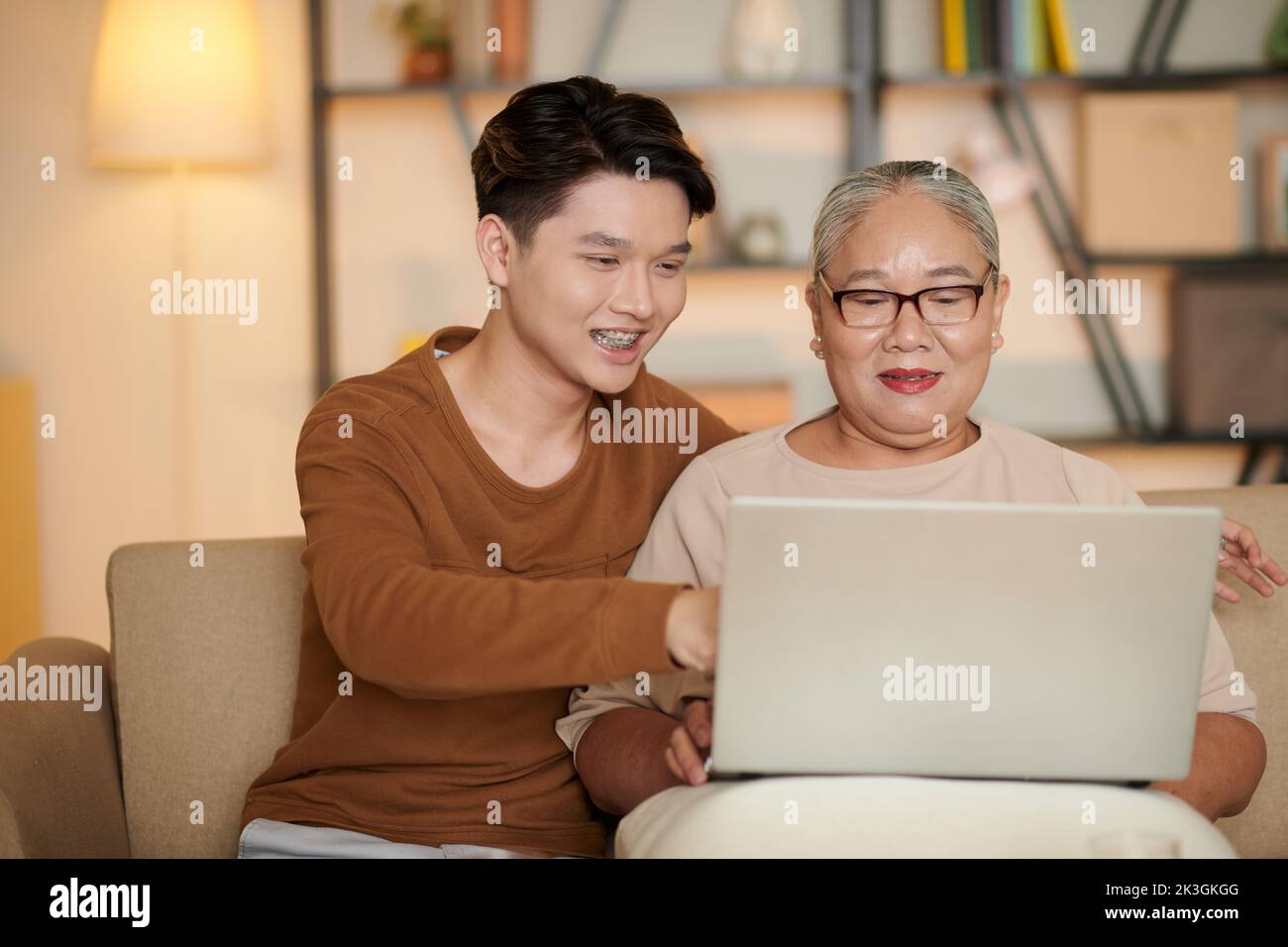 Smiling teenage boy with brackets helping grandmother learning how to ...