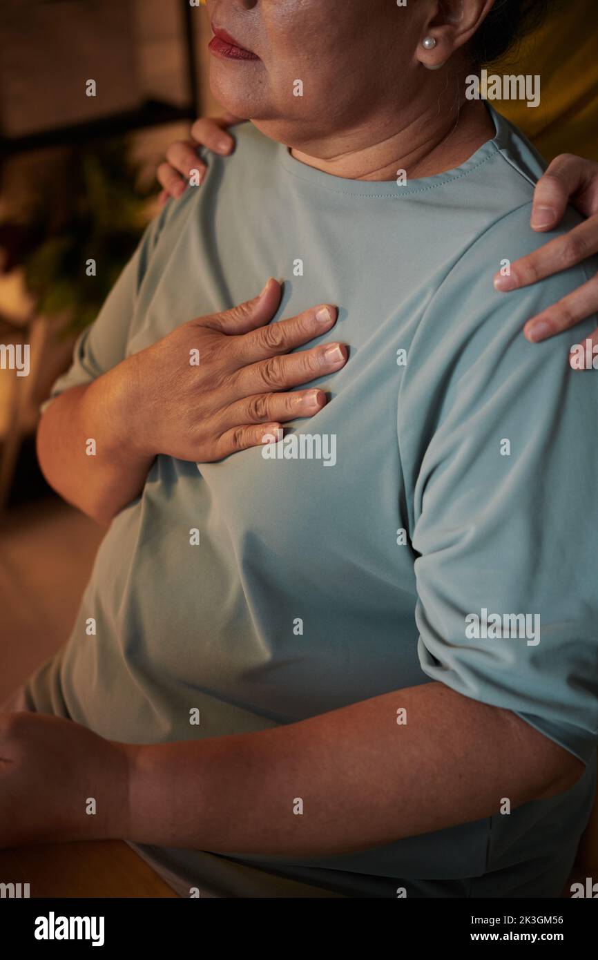 Worried senior woman touching chest when reading news article on ...