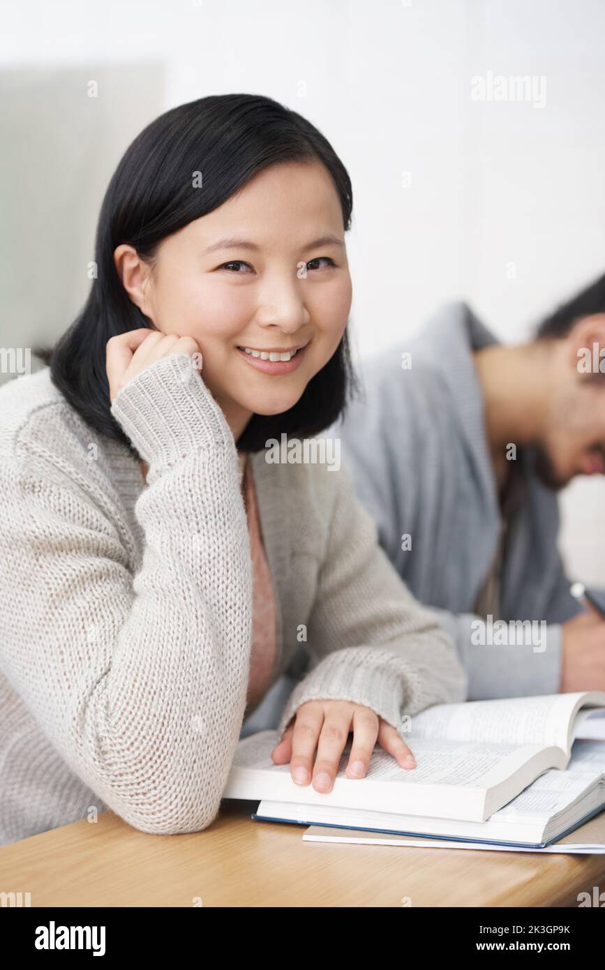 Knowledge is power. An Asian student smiling at the camera while she ...