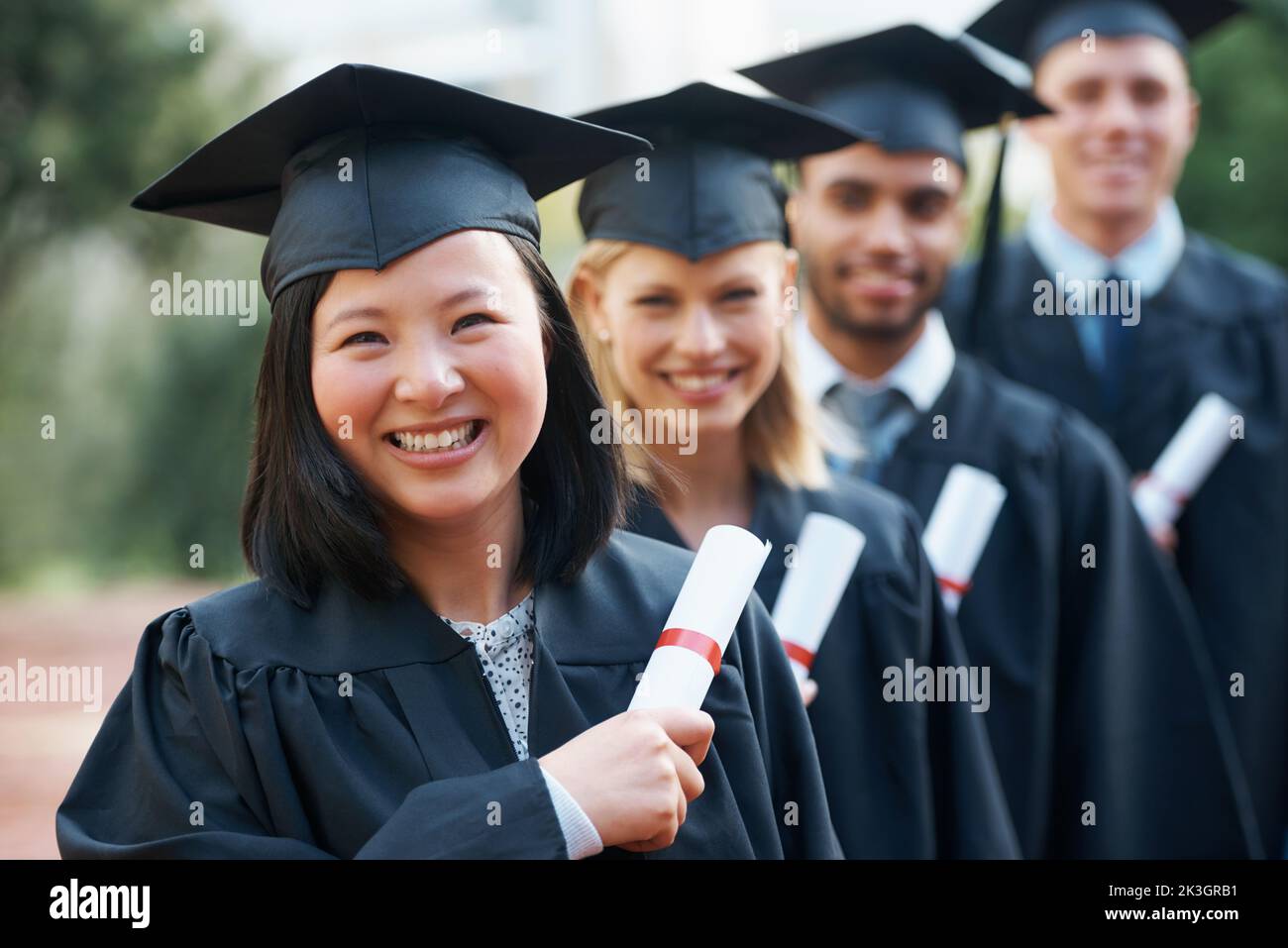 Honored to be graduates. Young college graduates holding their diplomas ...