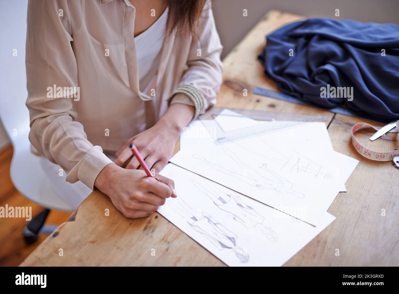 Coming up with new style trends. A fashion designer drawing sketches in ...