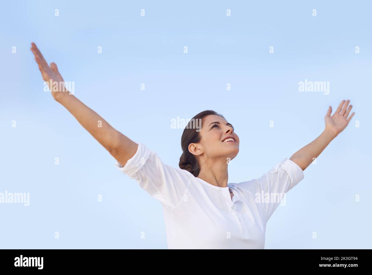 Feel the freedom. A young woman standing with her arms outstretched ...