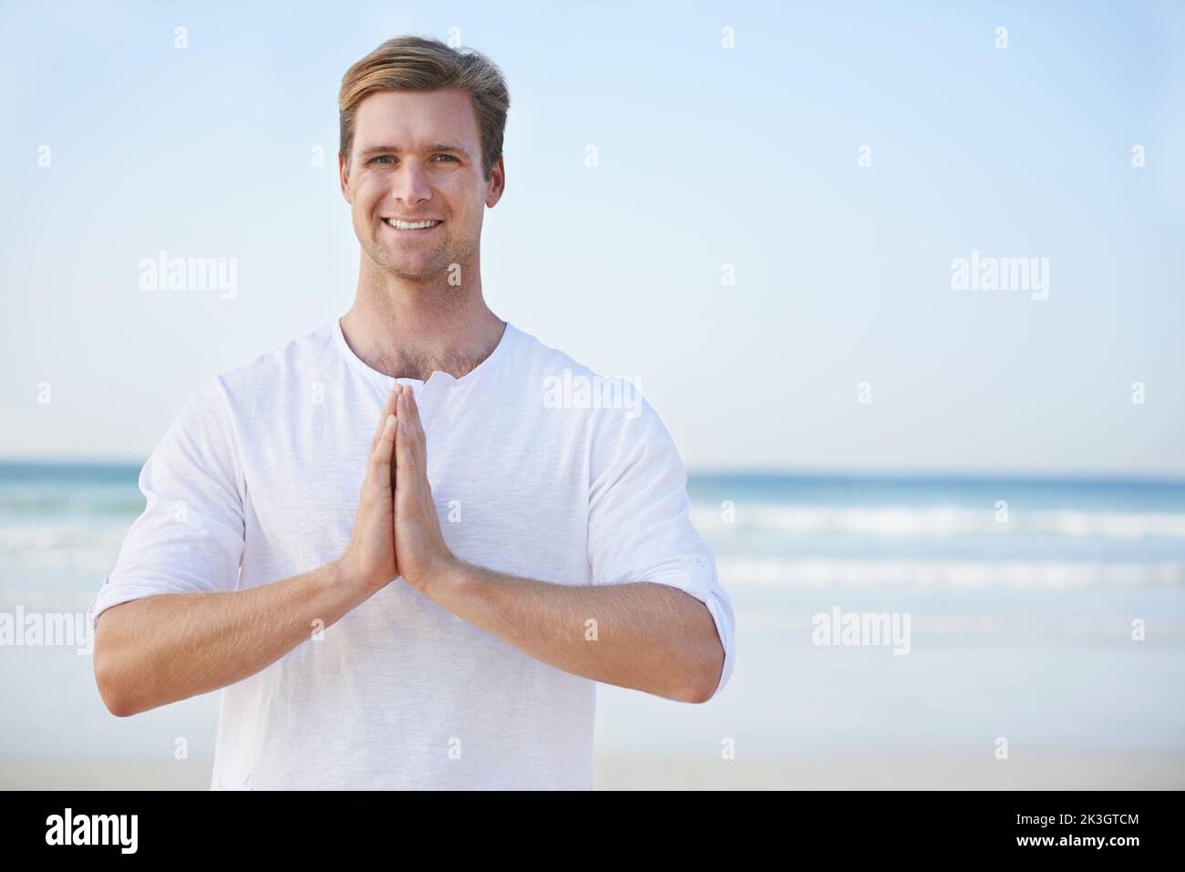 Seaside meditation. Portrait of a handsome young man meditating on the ...