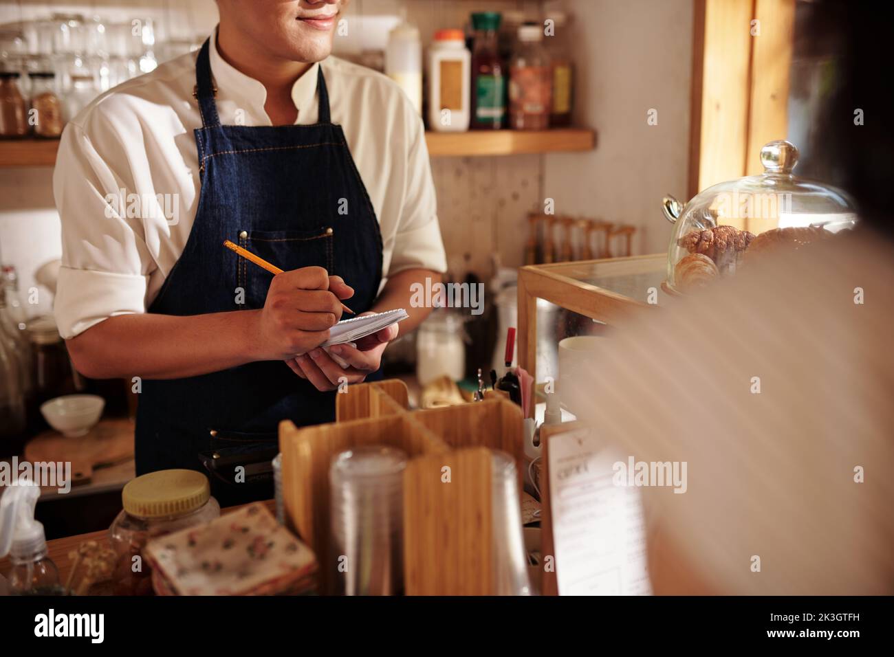 Coffeeshop waiter taking notes when accepting order from young woman ...