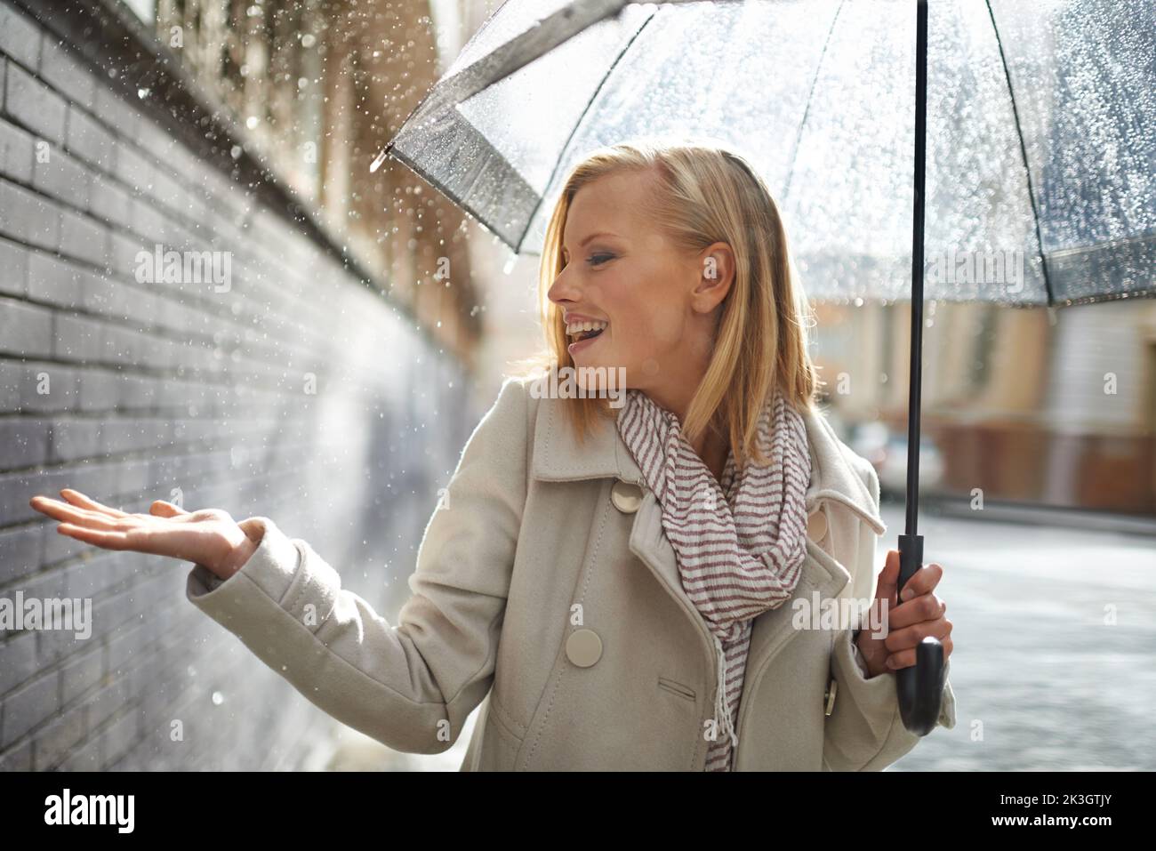 Enjoying a walk in the rain. a young woman walking down the street with ...
