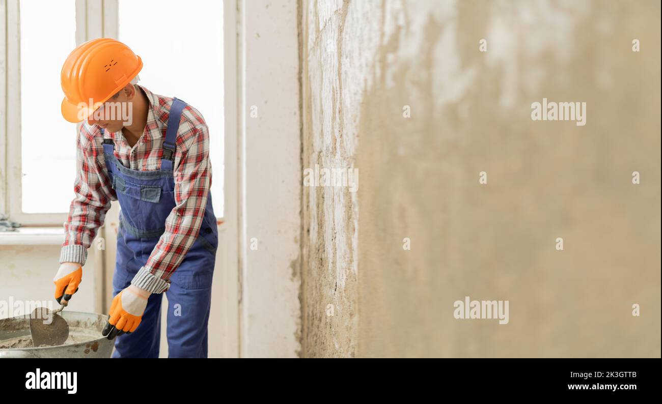 builder worker plasterer holding and using trowel to plastering cement ...