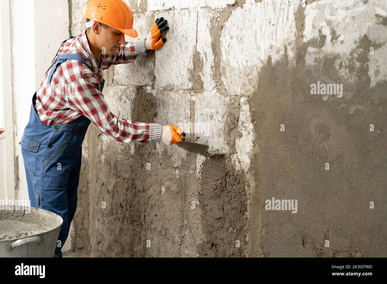 Construction worker plasterer with trowel plastering wall cement mortar ...