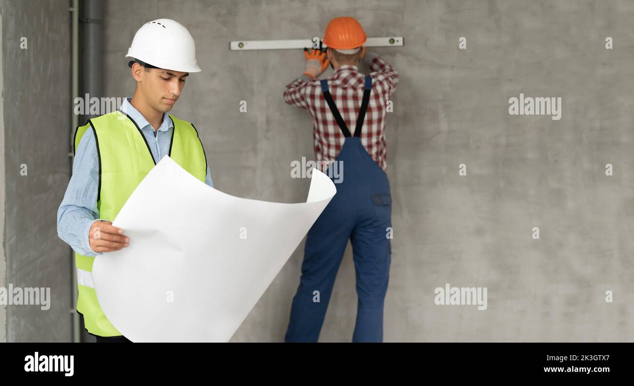 home repairs. Two young man architect with blueprint and builder with ...