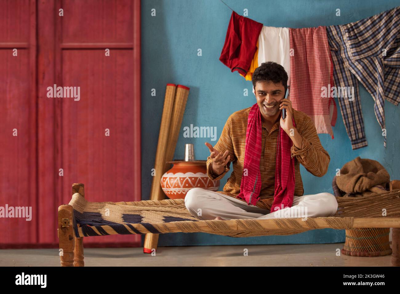 Happy man talking on mobile phone while sitting on cot Stock Photo - Alamy