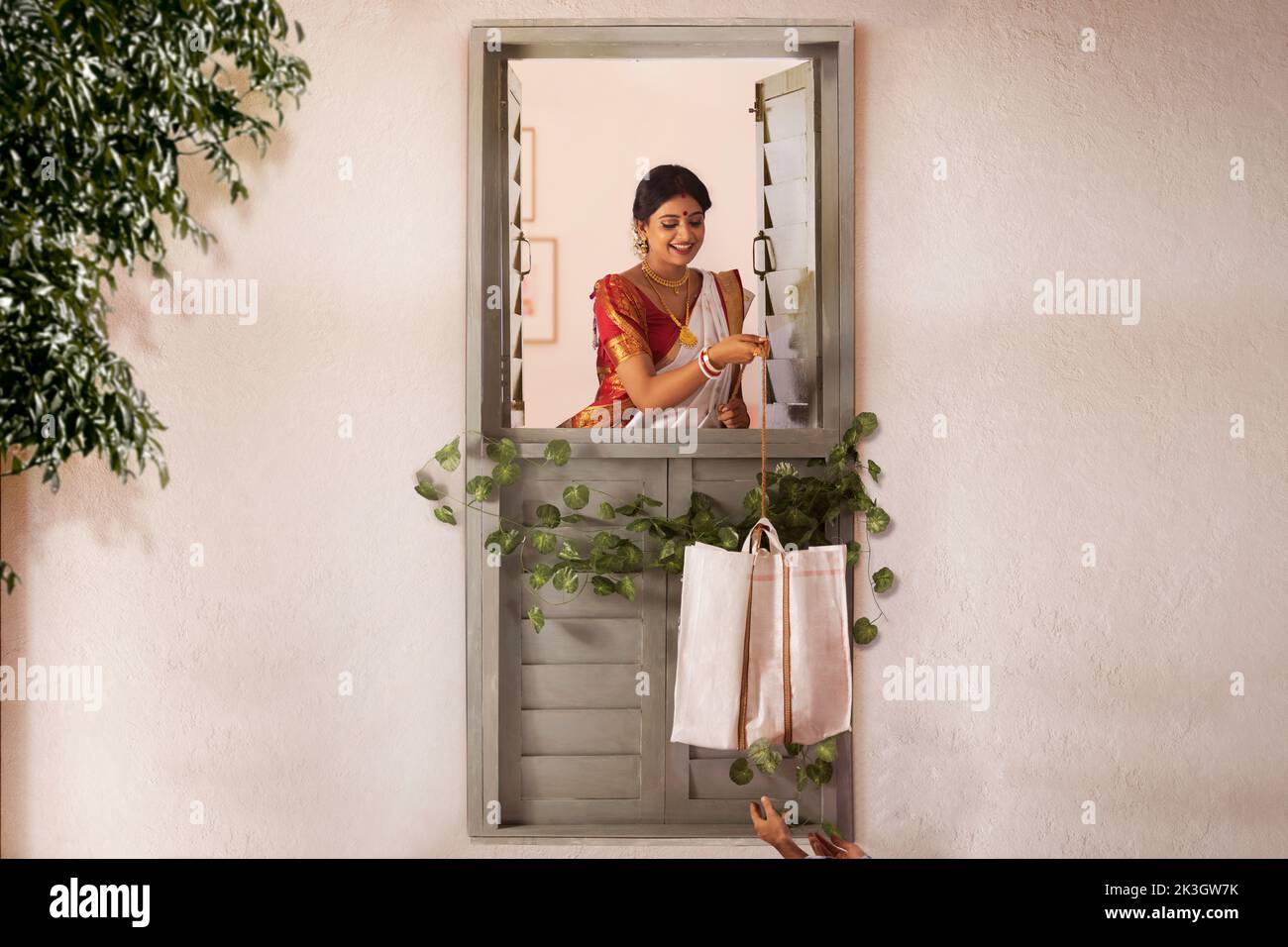 Bengali woman standing at the window and pulling the shopping bag with ...