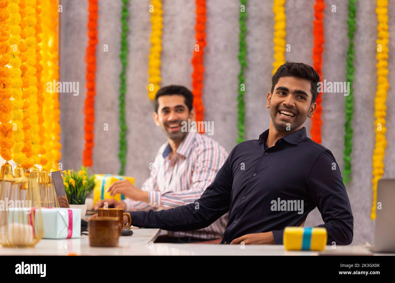 Happy employees looking elsewhere while working in office during Diwali ...