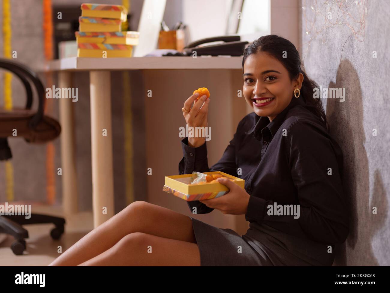 Female employee eating sweet in office during Diwali celebration Stock ...