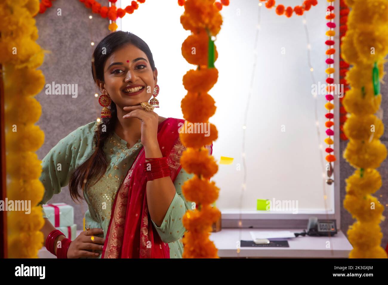 Female employee in traditional outfit gesturing in office during Diwali ...