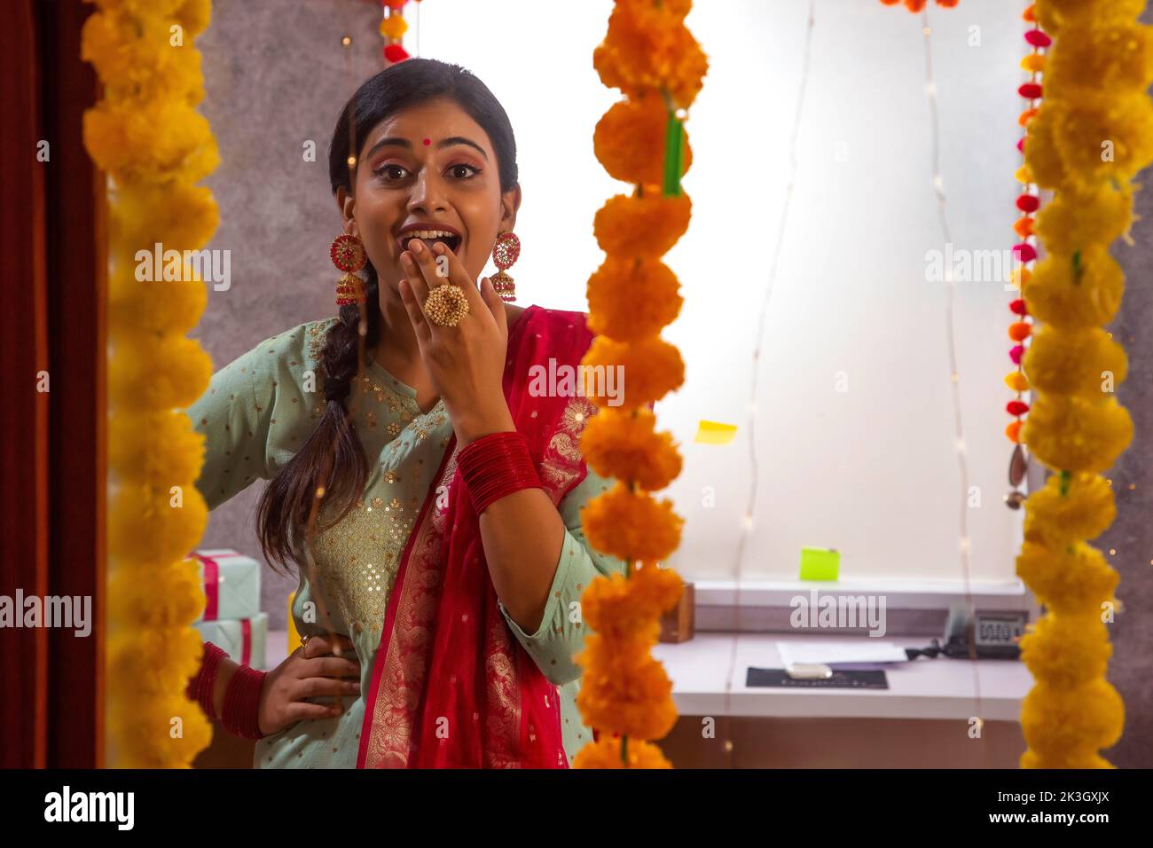 Female employee in traditional outfit gesturing in office during Diwali ...