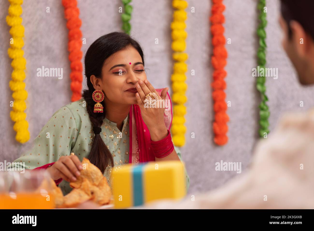 Woman eating samosa in office during Diwali celebration Stock Photo - Alamy