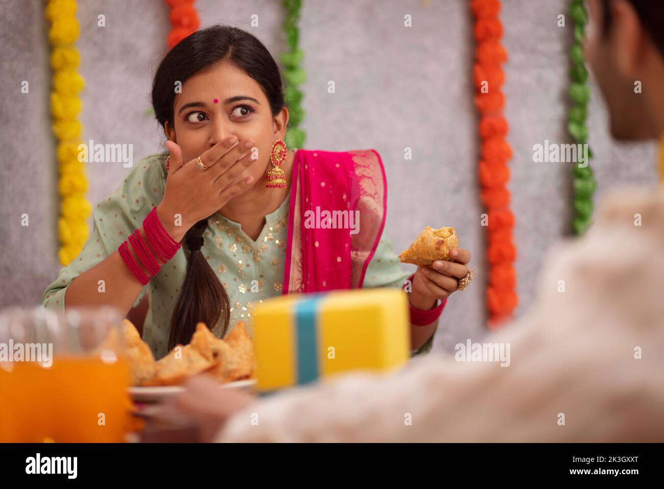 Woman eating samosa in office during Diwali celebration Stock Photo - Alamy