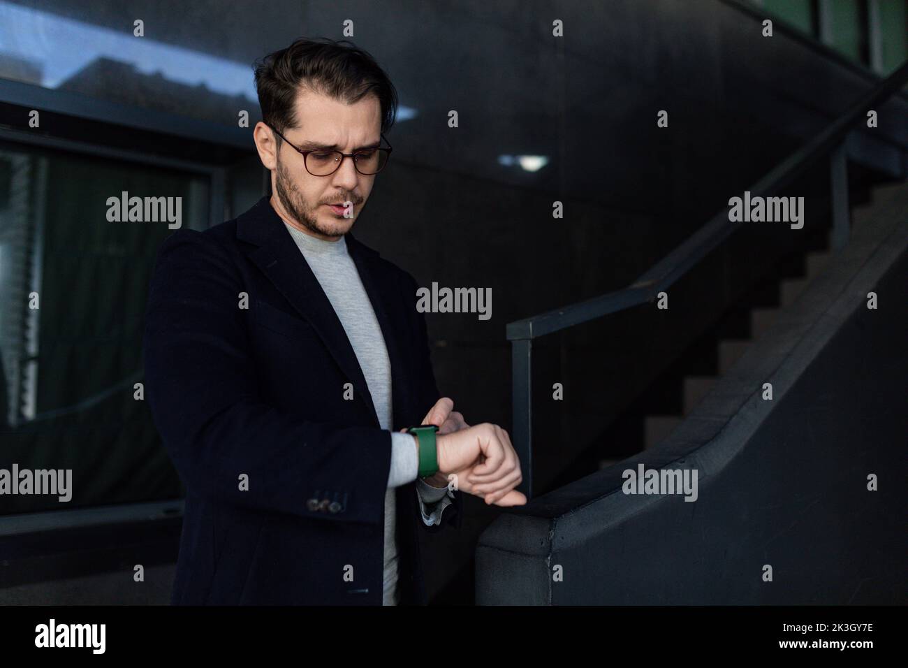 businessman looks at his watch on the background of the business center ...