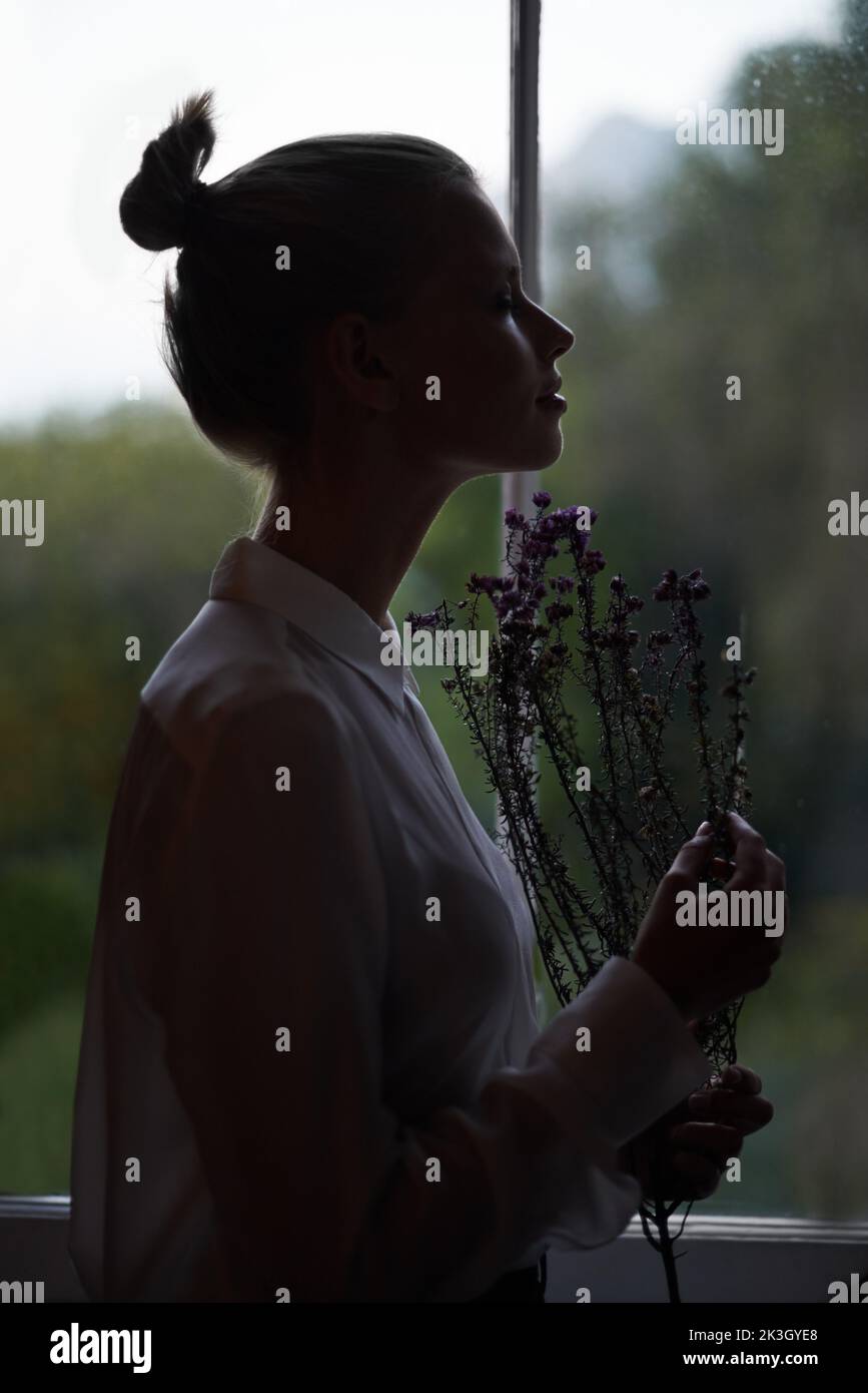 Let your imagination take flight. A young woman standing by a window ...