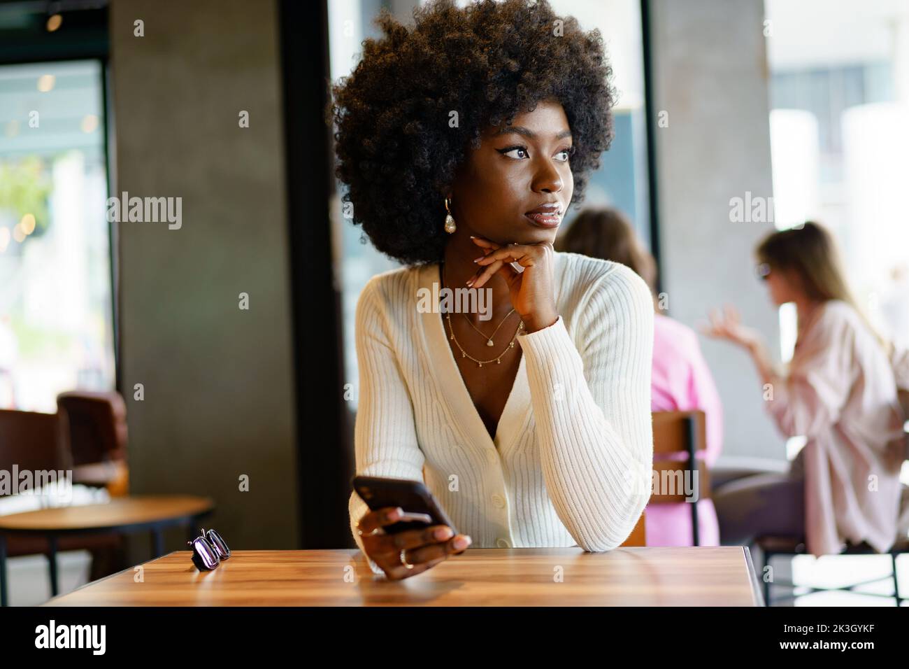 Young afro woman using mobile phone at coffee shop Stock Photo - Alamy