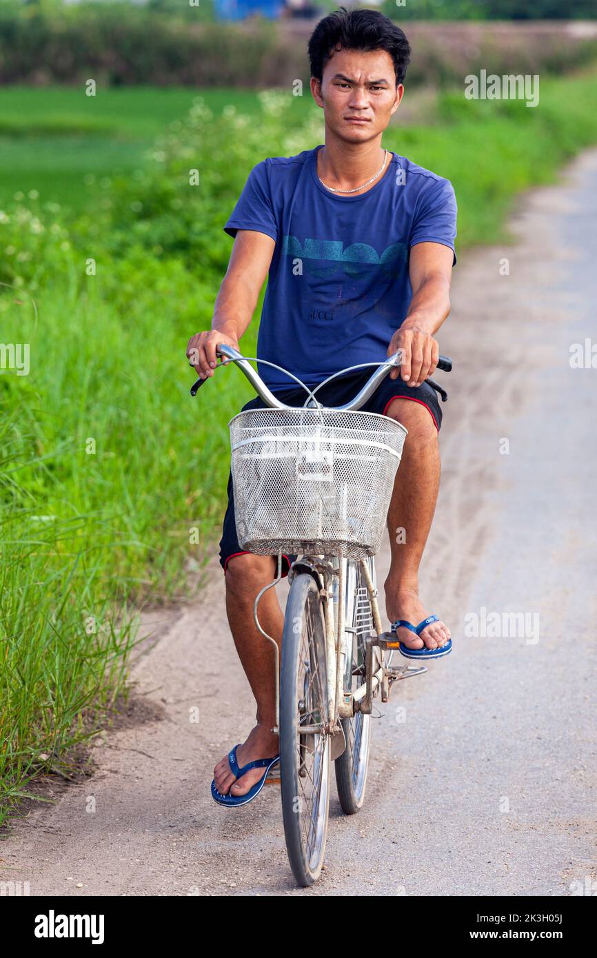 Young Vietnamese boy riding a bicycle on country road, rural Hai Phong ...