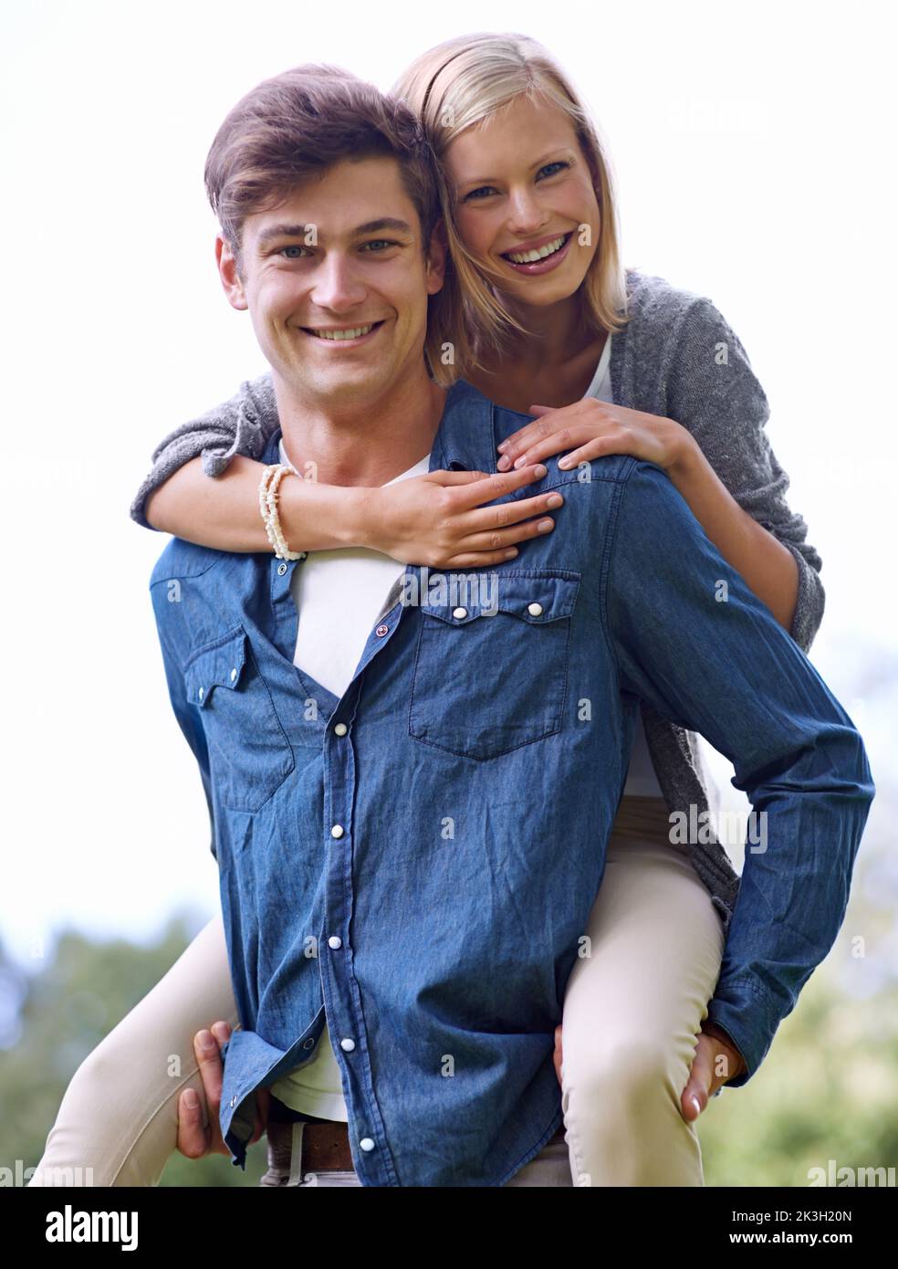 Playful piggybacking. A young woman recieving a piggyback ride from her ...