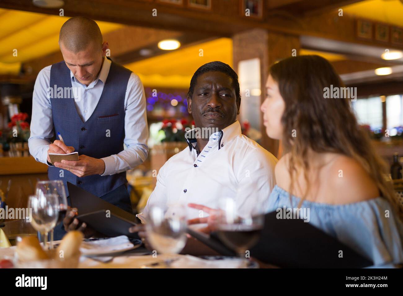 Male waiter carrying order for visitors in restaurant Stock Photo - Alamy