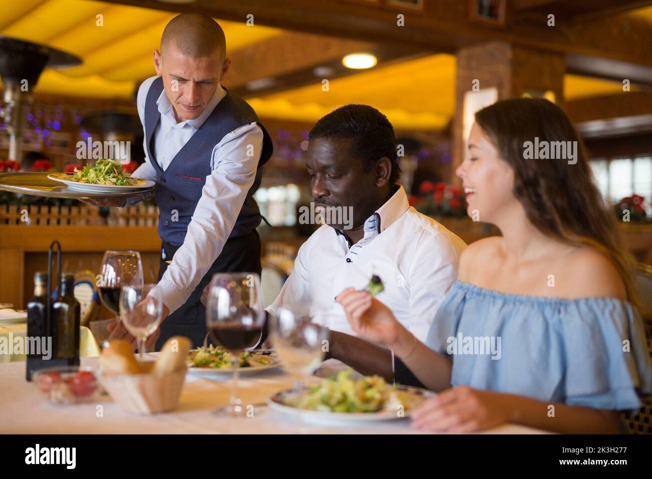 Male waiter carrying order for visitors in restaurant Stock Photo - Alamy