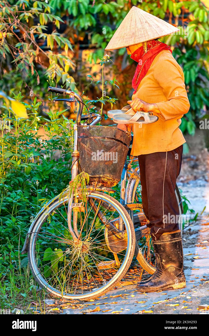 Vietnamese farmer with bicycle wearing bamboo hat in rural Hai Phong ...