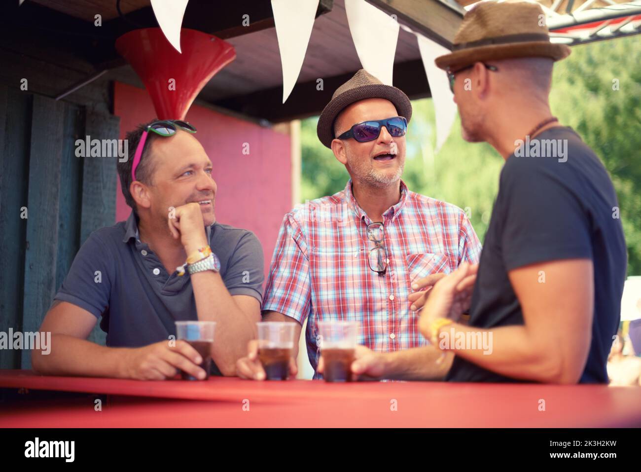 Sharing a drink amongst friends. three male friends talking and having ...