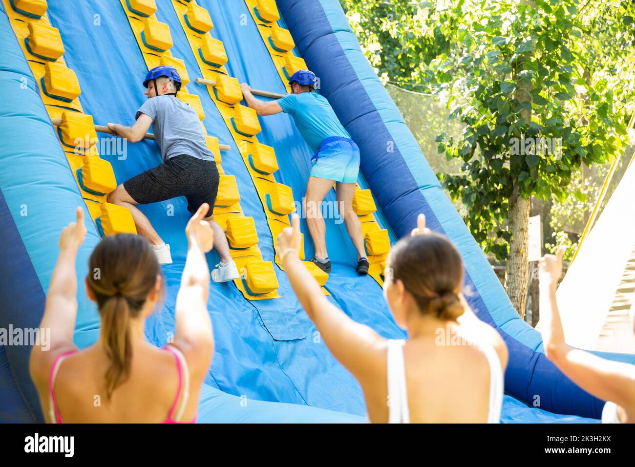 Men climbing up on slide in adventure park Stock Photo - Alamy