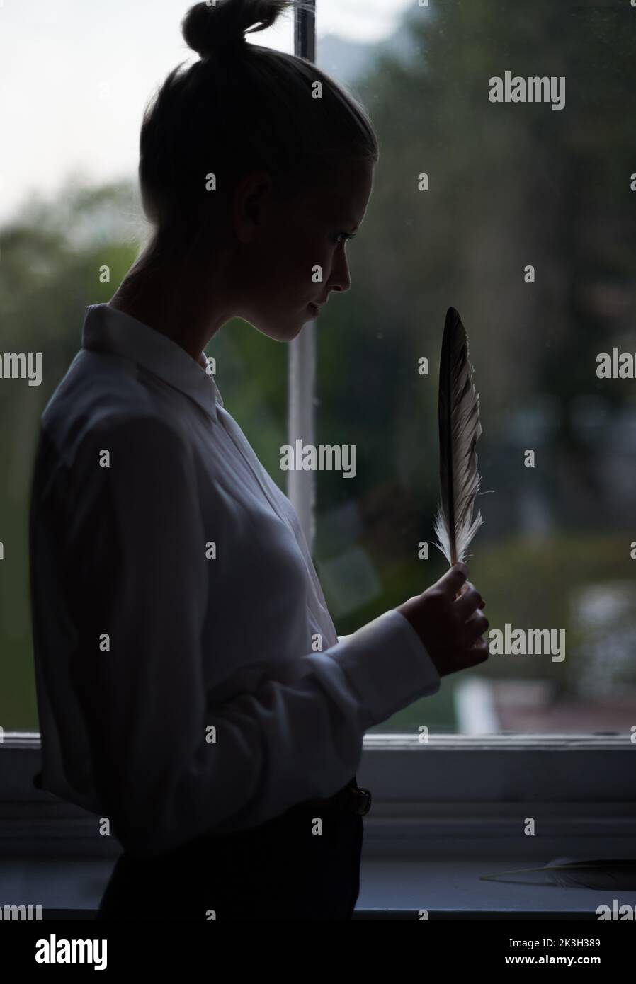 Let your imagination take flight. A young woman standing by a window ...