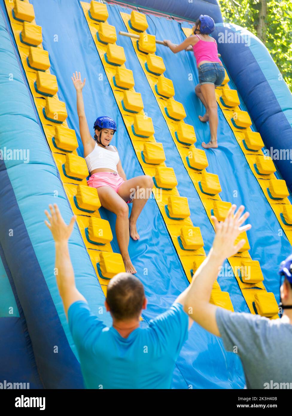Happy girl sliding down inflatable slide in outdoor amusement park ...