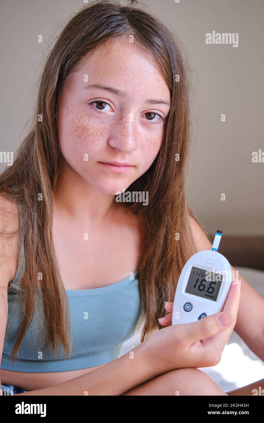 A teenage girl shows the screen of a glucometer with the results of a ...