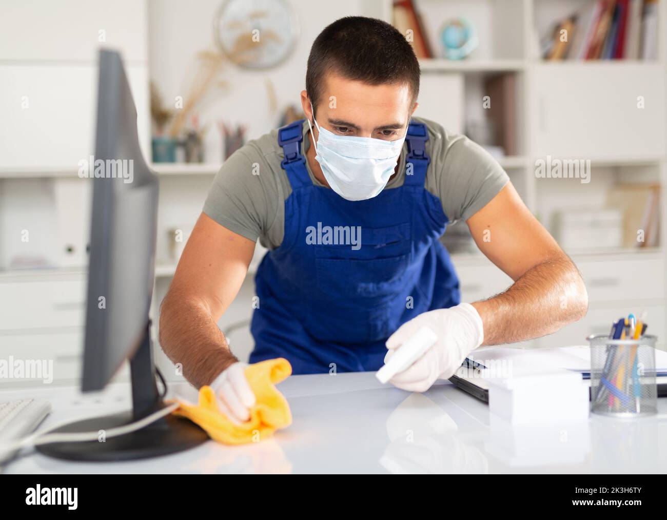 Cleaning worker in face mask wiping office desk Stock Photo - Alamy