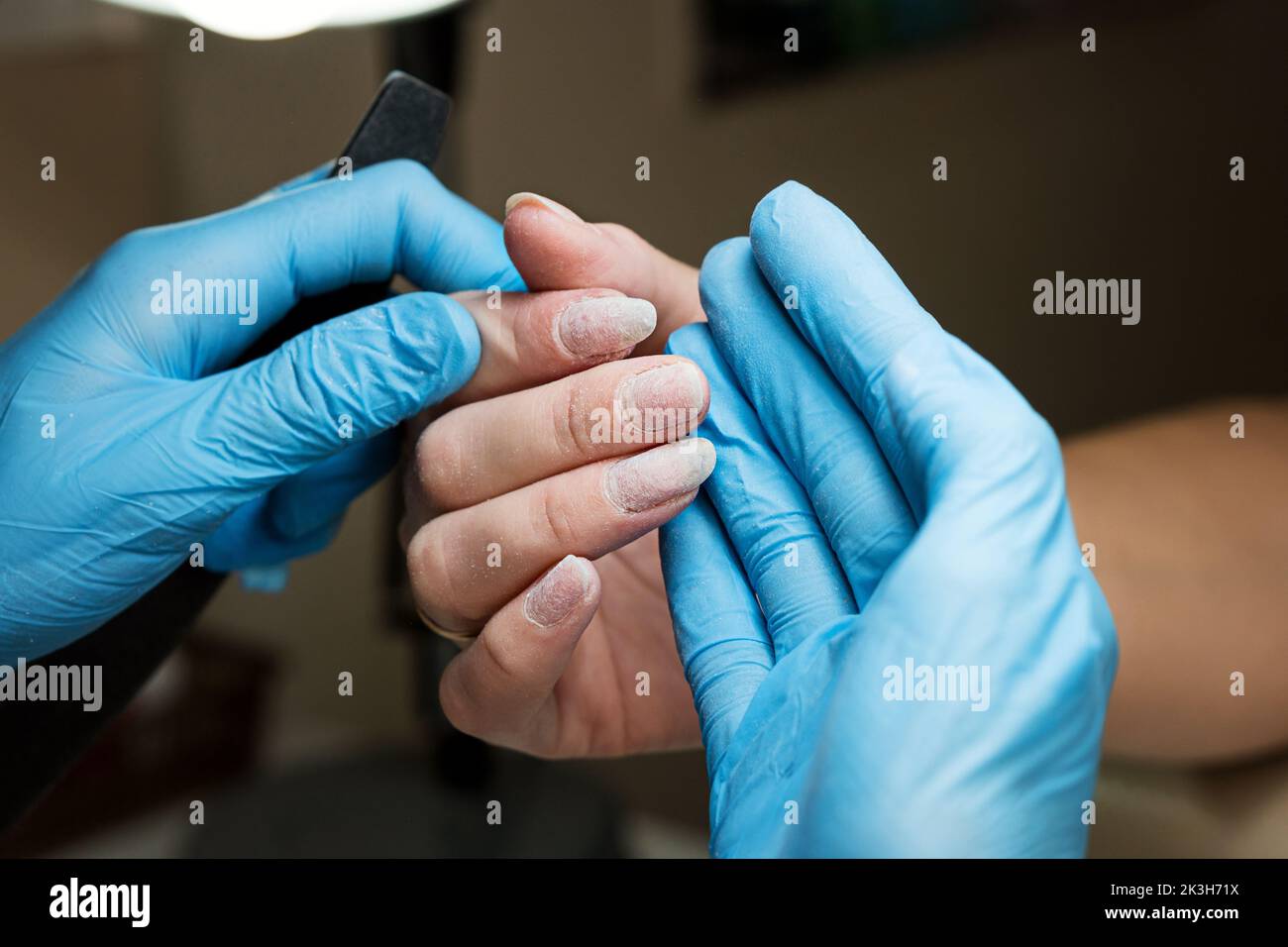 Close-up image manicurist in blue gloves holds client hand, examines ... Close-up image manicurist in blue gloves holds client hand, examines ...