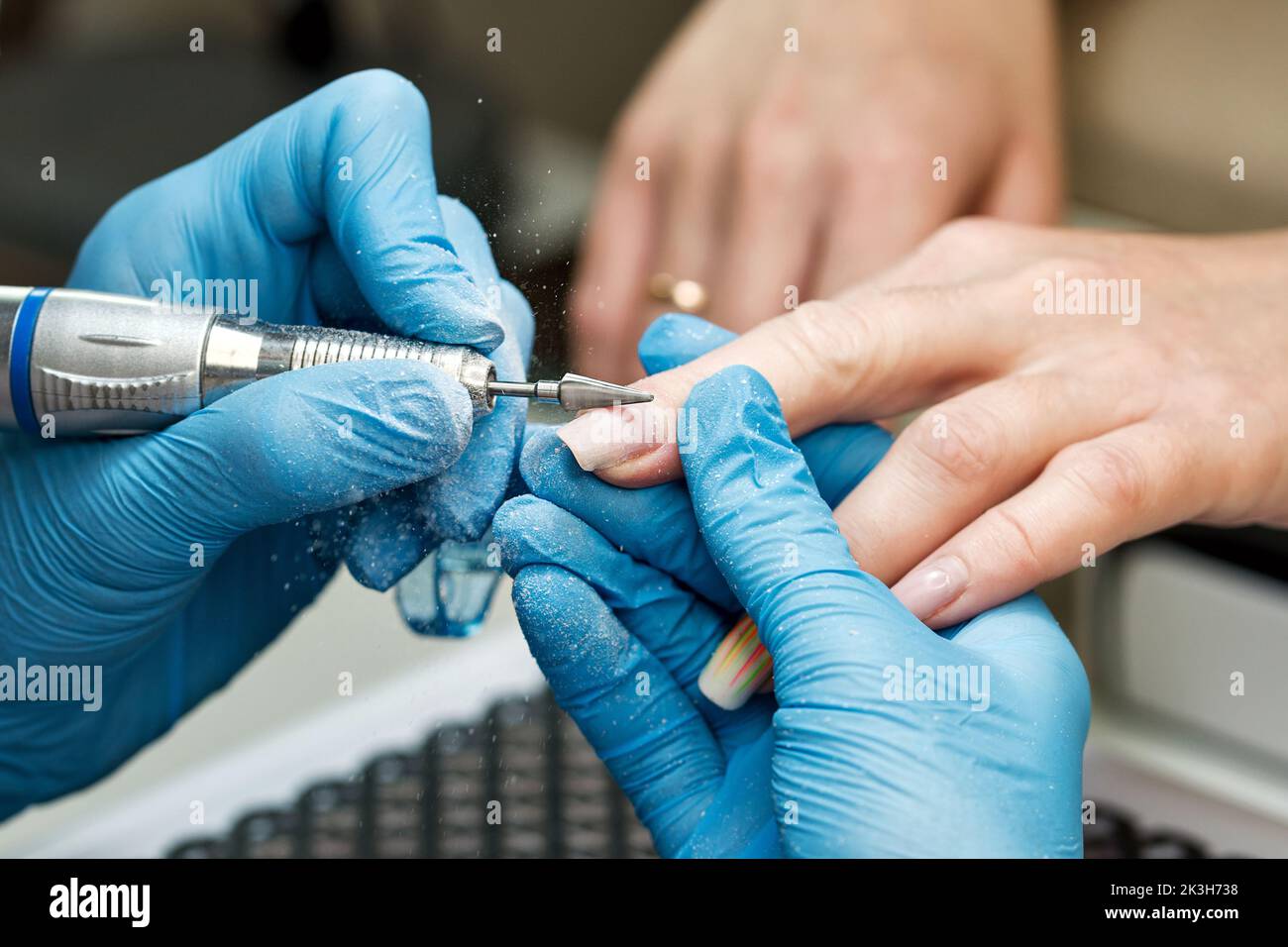 Process hardware manicure. Manicurist in blue gloves works with milling ...