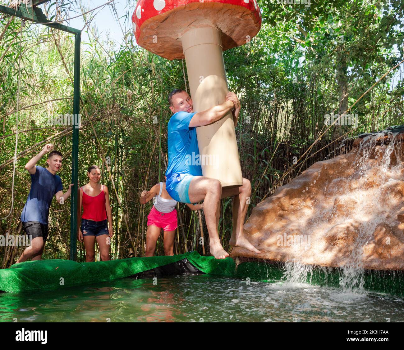Man flying over water pool holding to big mushroom in amusement park ...