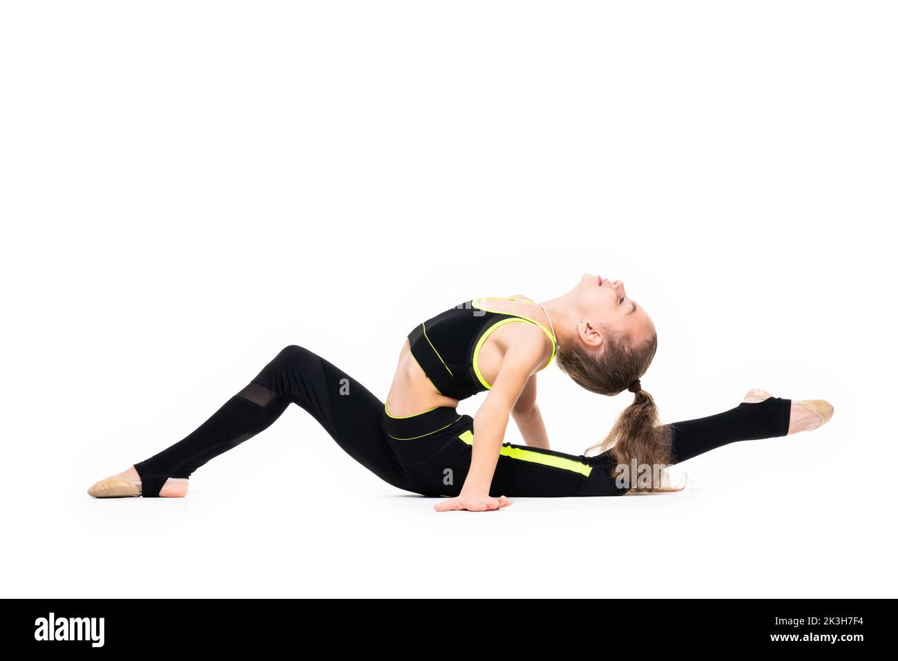 Gymnastic exercises. A flexible little girl in a black tracksuit arches ...