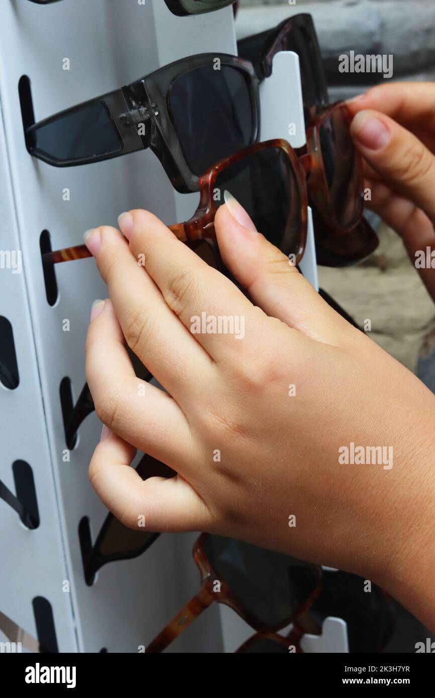 Person choosing sunglasses from street display in optical shop. Hand ...