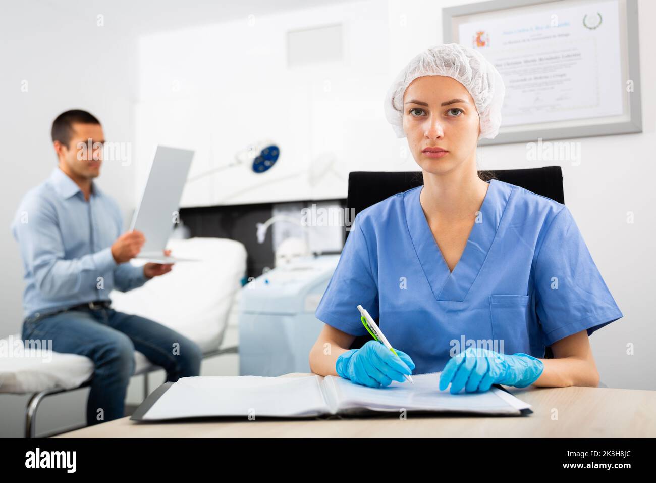 Woman beautician writing notes, man patient on background Stock Photo ...