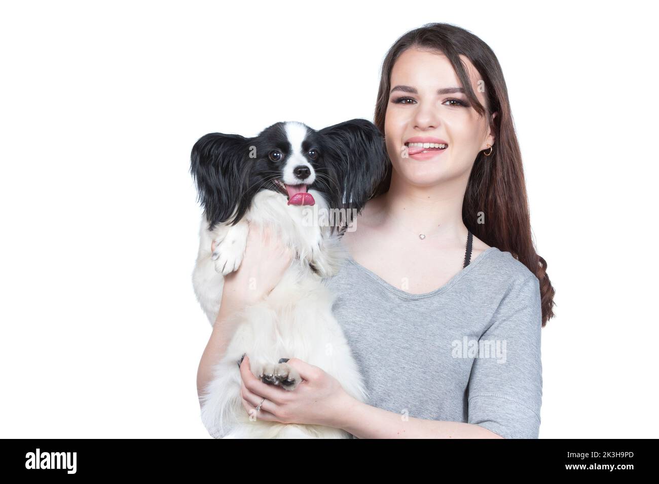 A cute young woman is hugging her papillon puppy. Love between owner ...