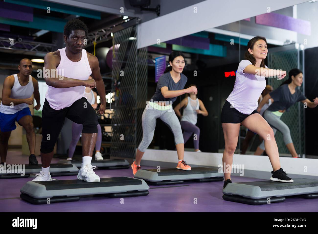 African american man in group of people working out with steppers in ...