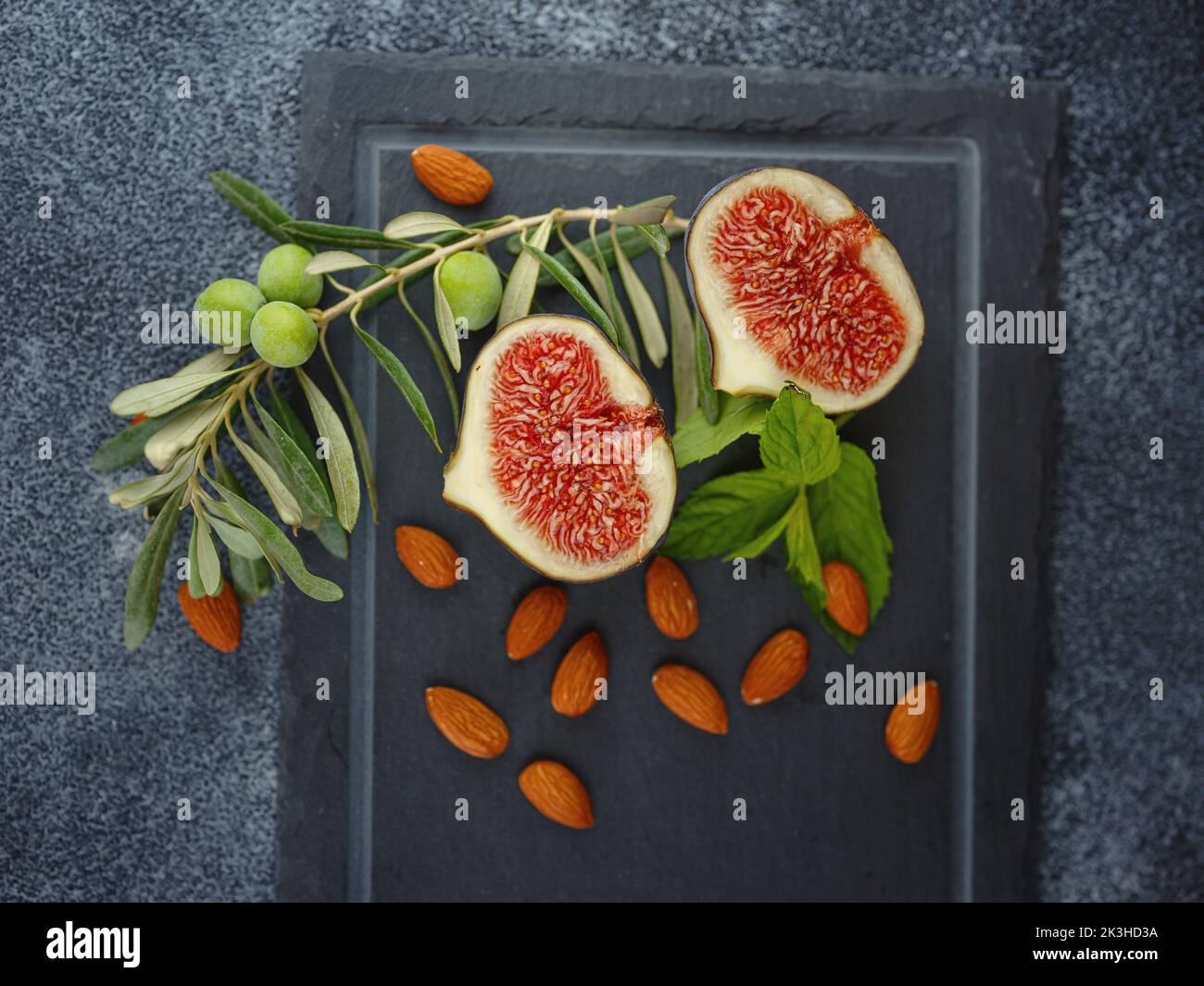 fresh ripe figs fruit almond nuts and olive branch on dark table ...