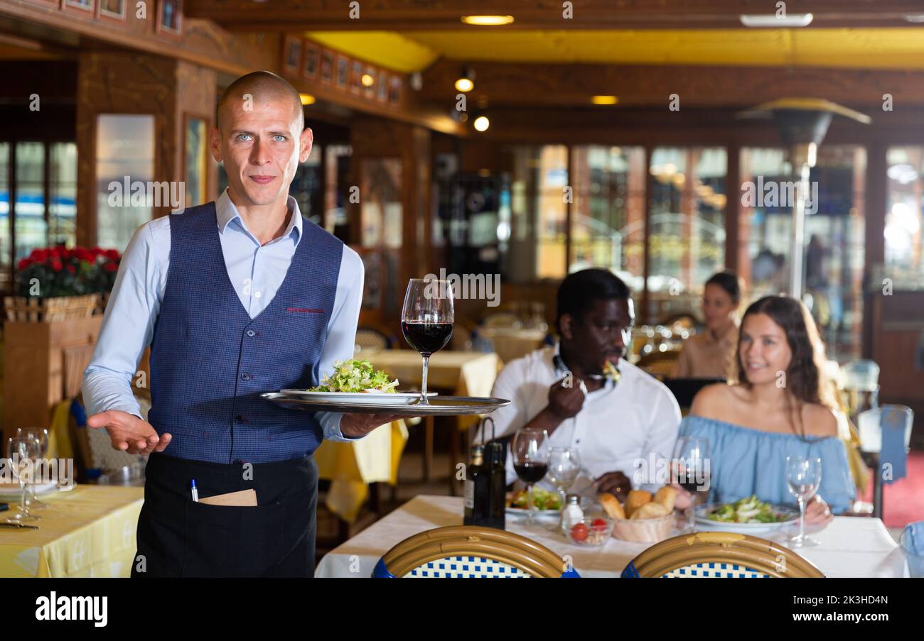 Waiter standing with serving tray, recommending dishes in restaurant ...