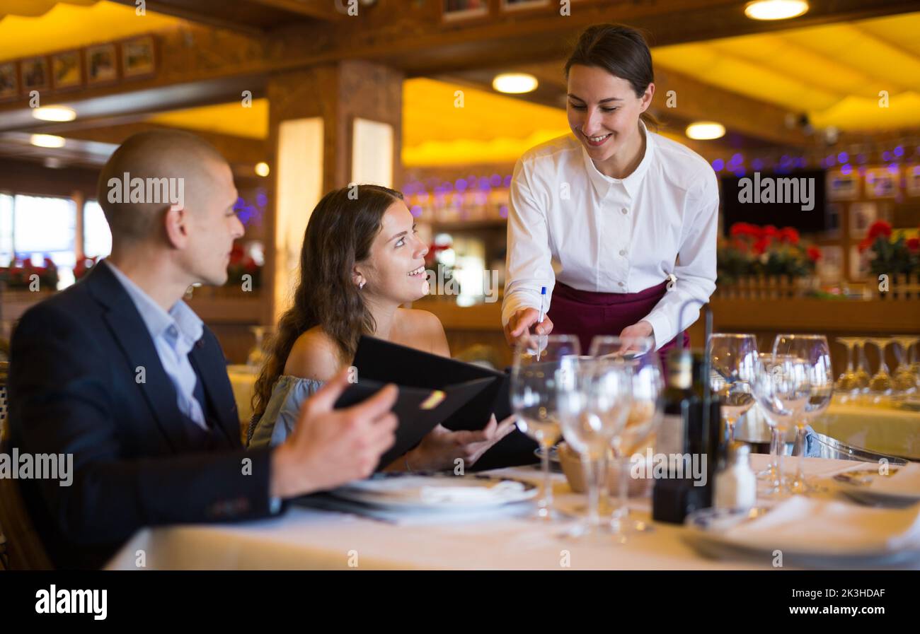 Woman waiter is taking order from clients in restaurante Stock Photo ...