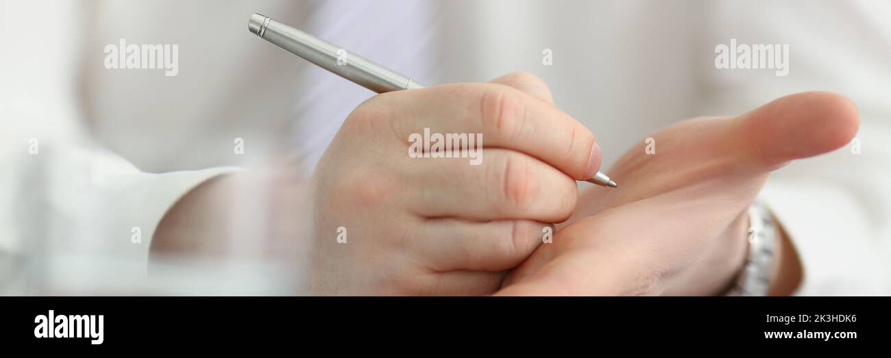 Male writing note with silver pen on his hand to keep in mind some ...