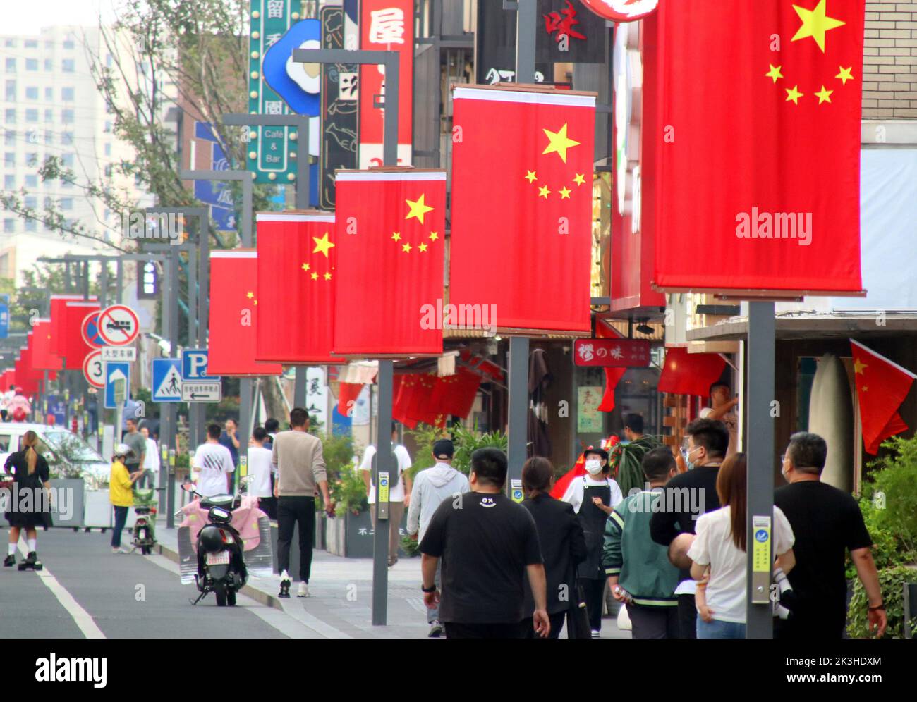 SUZHOU, CHINA - SEPTEMBER 26, 2022 - People pass under national flags ...